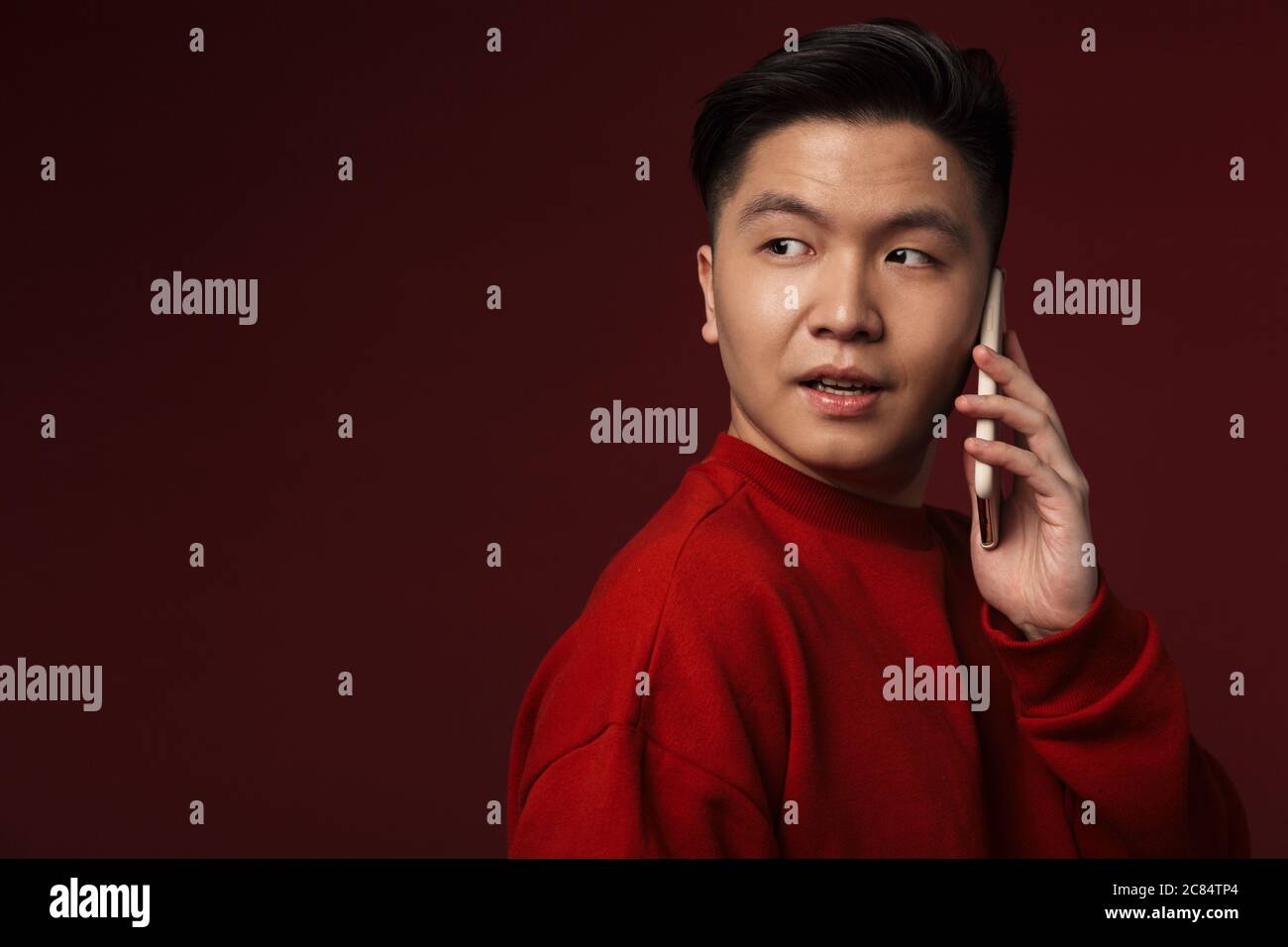 Image of serious handsome asian man talking on mobile phone isolated ...