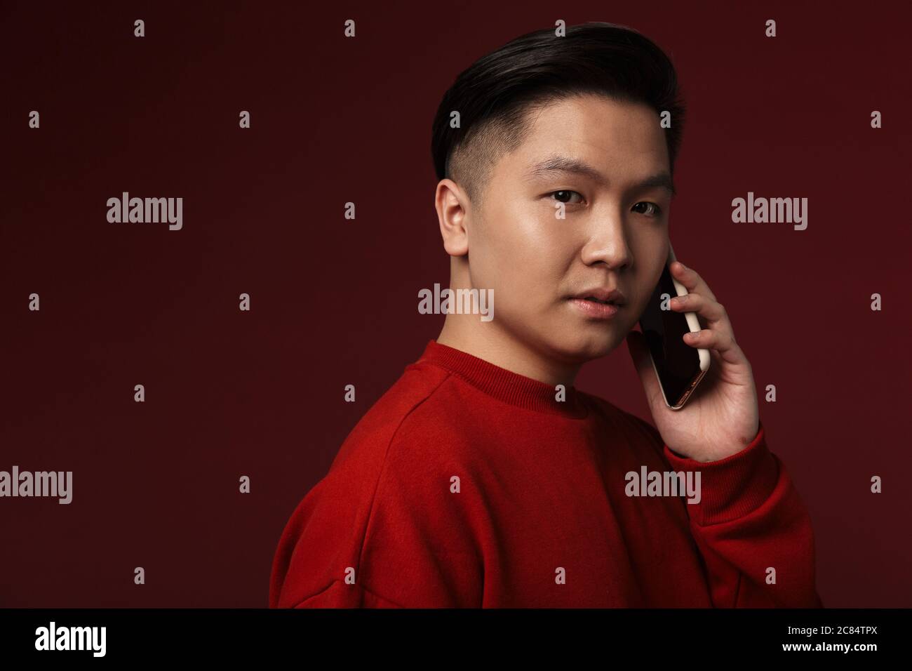 Image of serious handsome asian man talking on mobile phone isolated ...