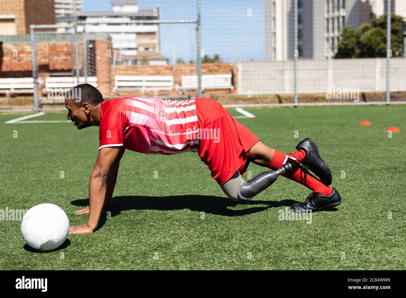 Mixed race male football player with prosthetic leg wearing a team ...