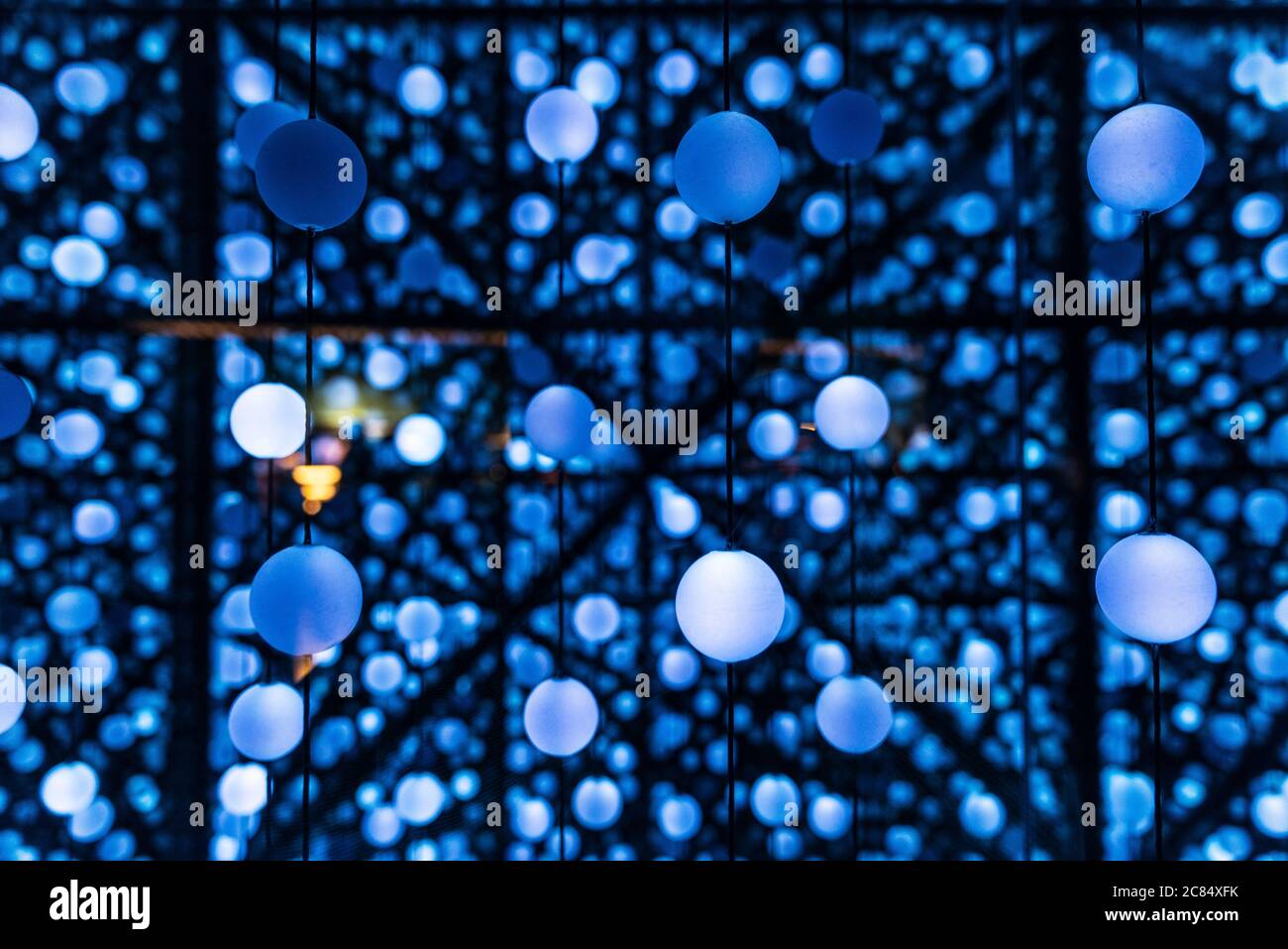 Many illuminated balls hung and linked by threads creating an infinite ...