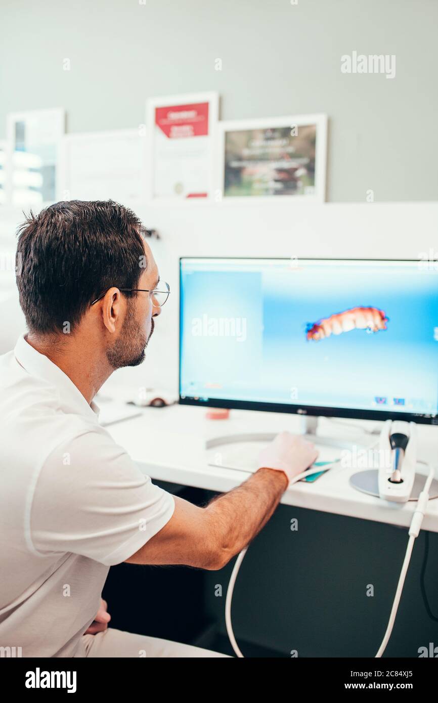 Doctor dentist on a computer models the jaw to develop the shape of a ...