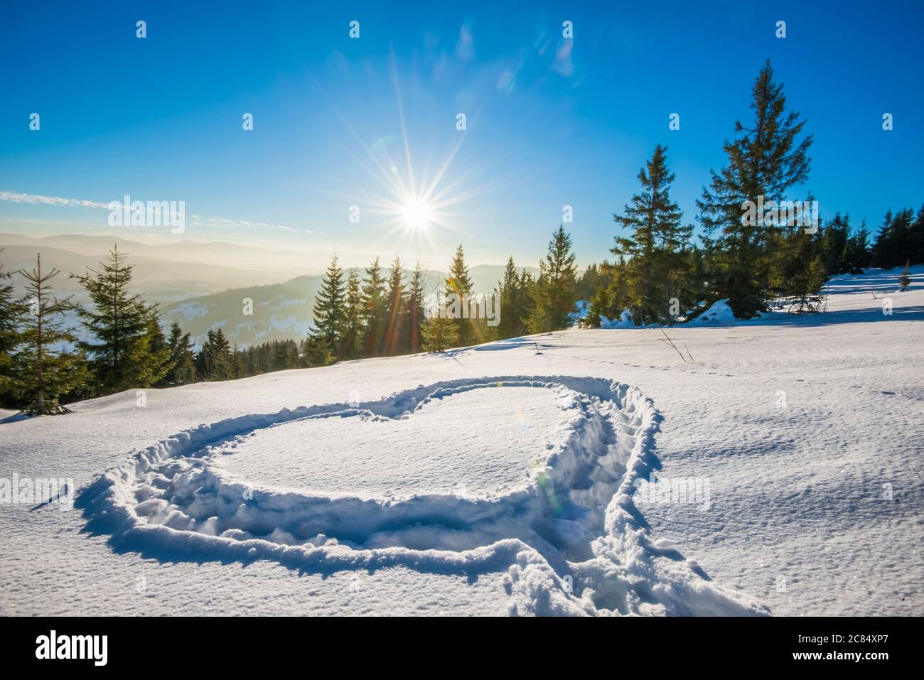 Heart trampled on the snow with feet in a snowdrift on a hillside with ...
