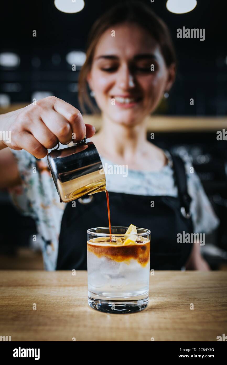 Barista girl prepares a refreshing summer version of iced and syrup ...