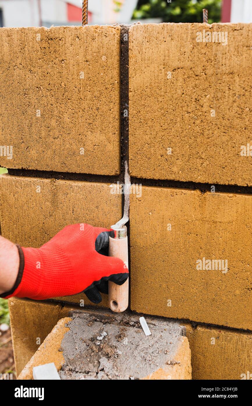 Hands of a professional bricklayer with gloves while working on the ...
