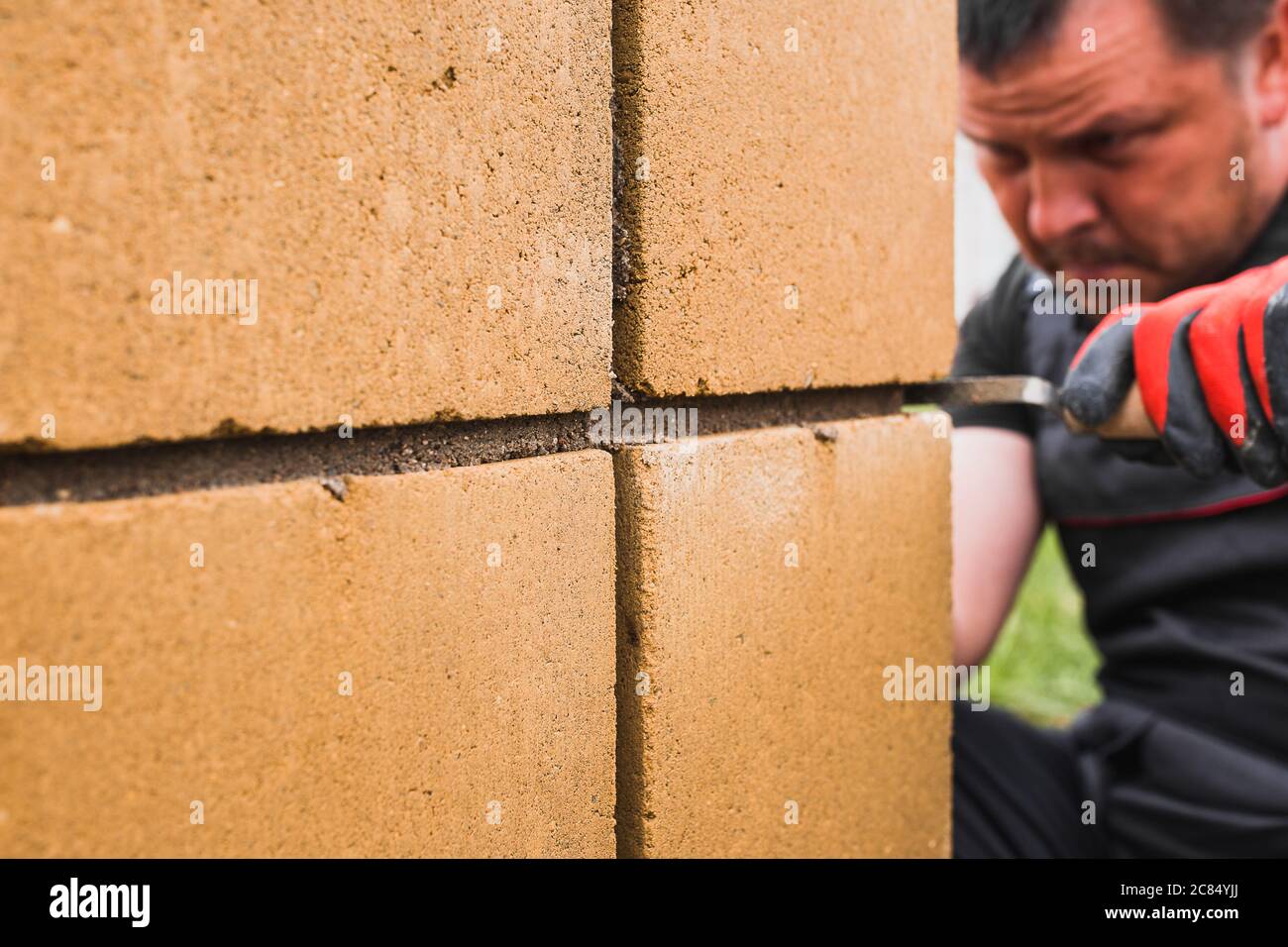 Hands of a professional bricklayer with gloves while working on the ...