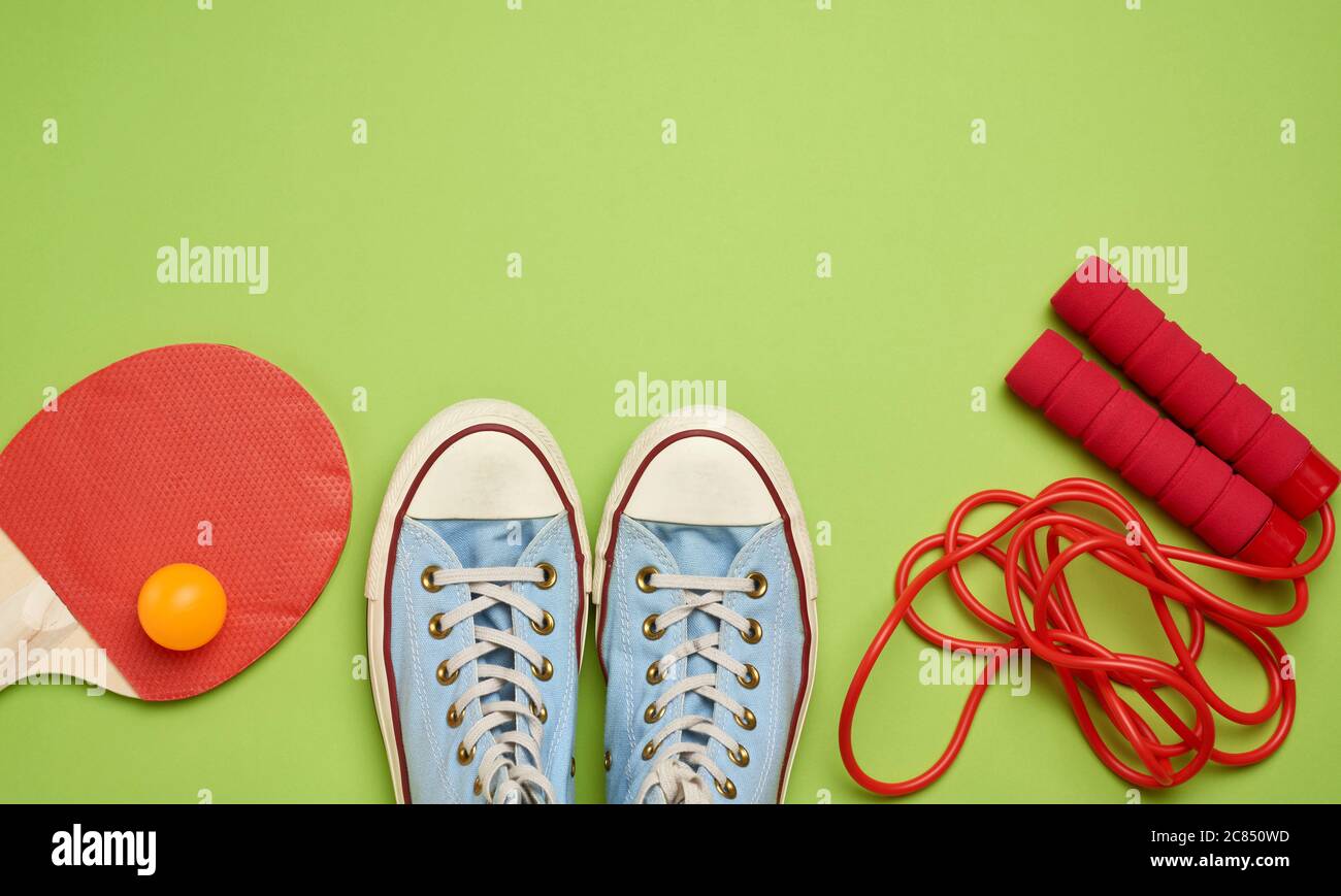sneakers, jump rope and wooden rackets for table tennis on a green ...