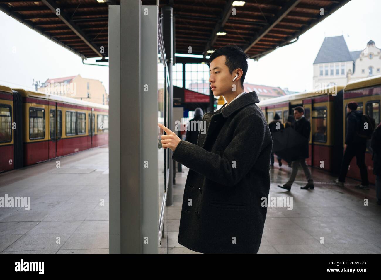 Young stylish Asian businessman in thoughtfully watching timetable of ...