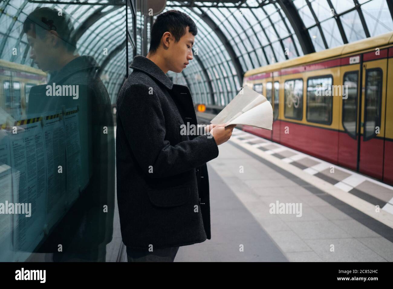 Side view of young stylish Asian businessman confidently reading ...