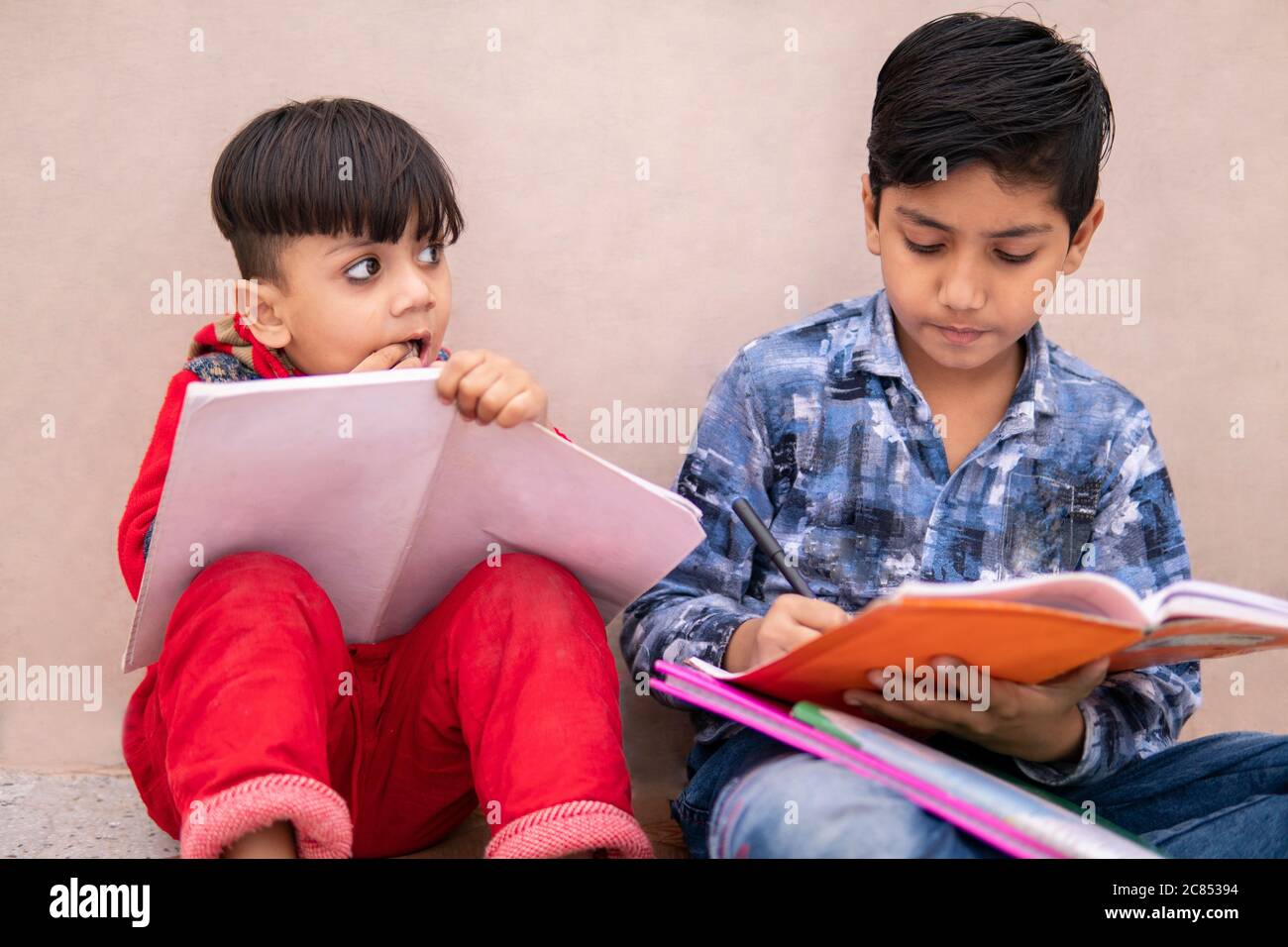 Little brothers studying together and writing on notebook Stock Photo ...