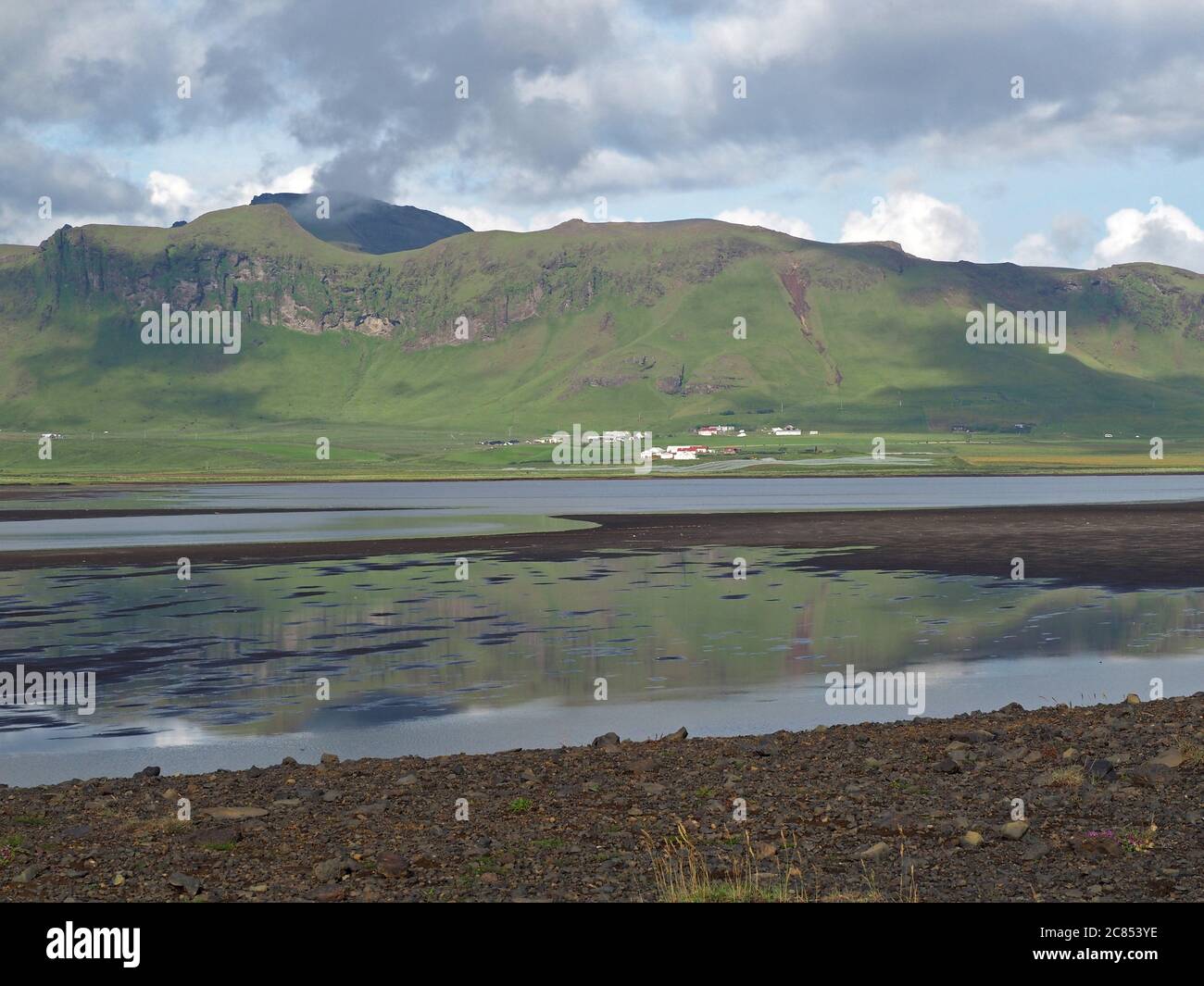 iceland green hills near Vik village with shallow water lake and dark ...
