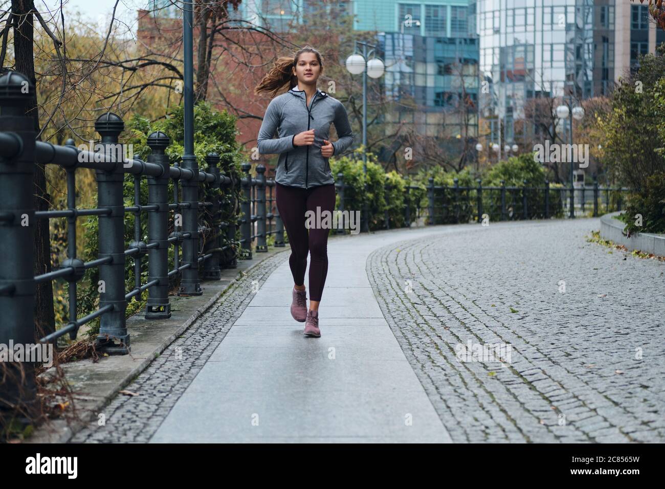 Attractive sporty girl running through city street Stock Photo - Alamy