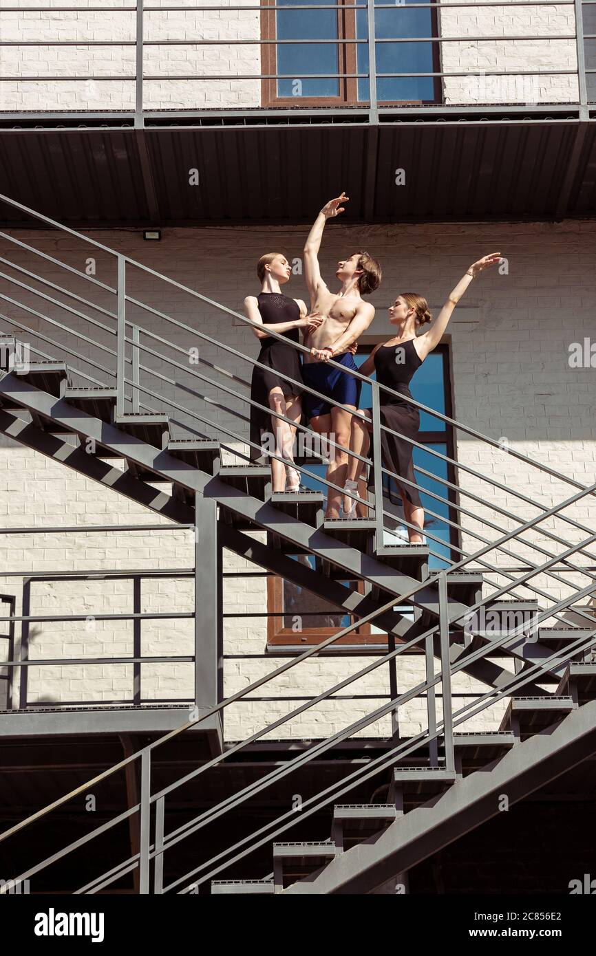 The group of modern ballet dancers performing on the stairs at the city ...