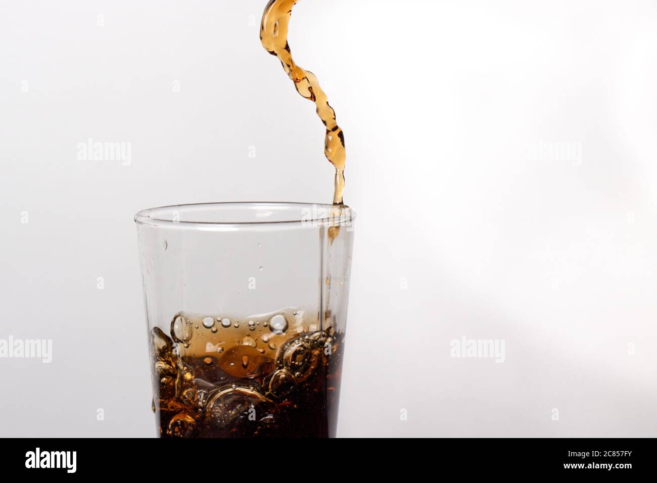 A brown dark sweet drink is poured into a glass beaker, spatter and a ...