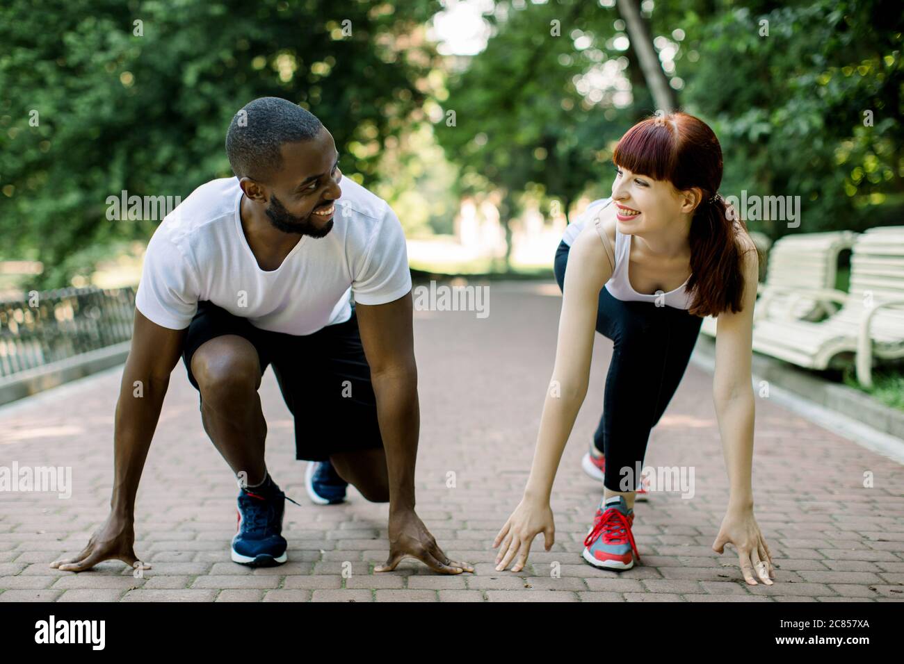 Multiethnic couple in sport clothes on starting line preparing to run ...