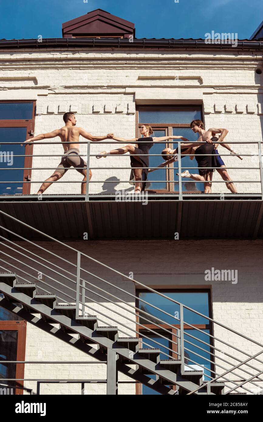 The group of modern ballet dancers performing on the stairs at the city ...