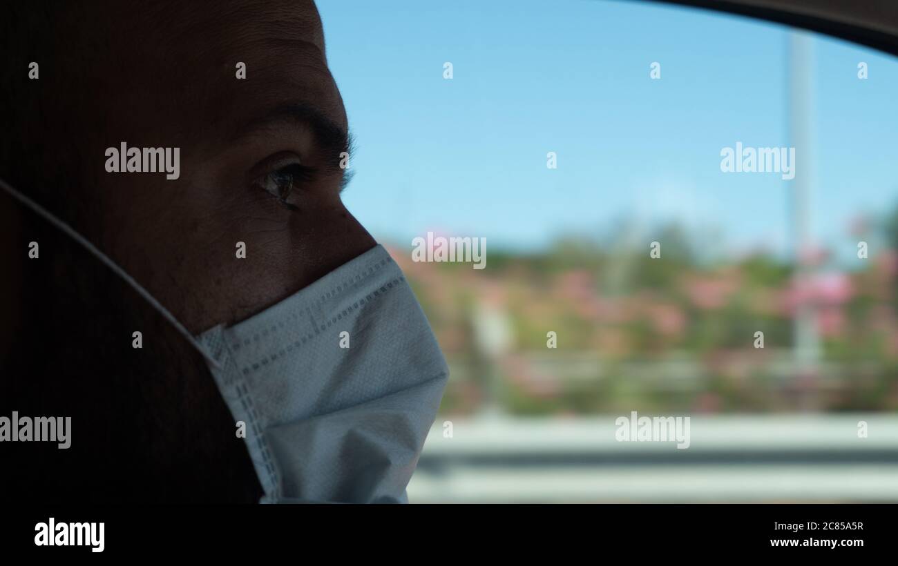 Man wearing a protective white face mask while driving a car Stock ...