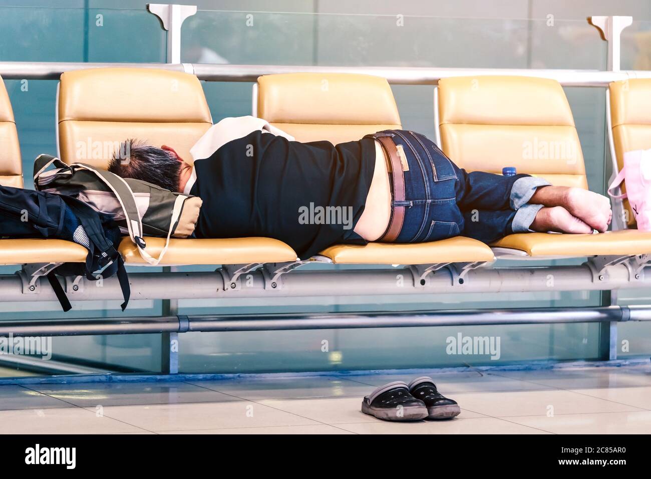 Tired Passenger Napping On A Benches While Waiting For Boarding In The