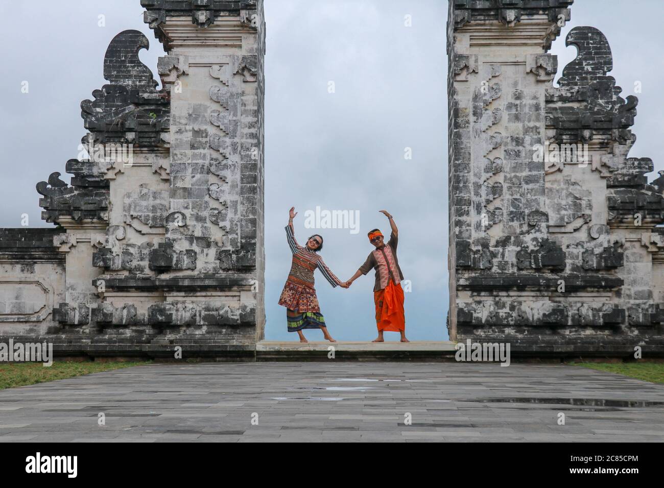 Happy young couple staying in temple gates of heaven and holding hands ...