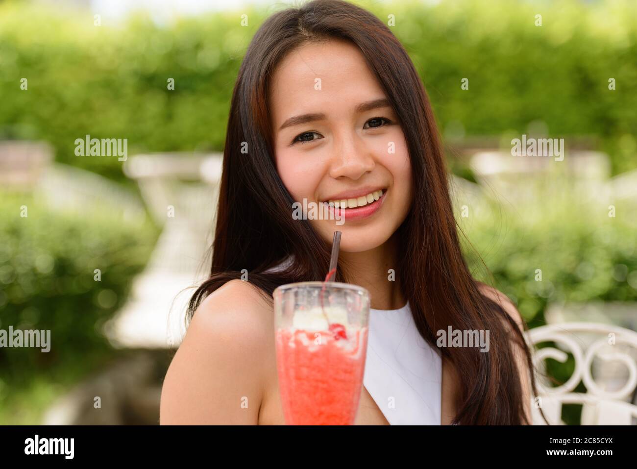 Happy young beautiful Asian woman with milkshake at the coffee shop ...