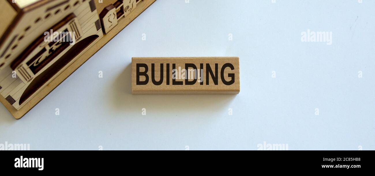 Wooden block form the word 'building' near miniature house. Beautiful ...
