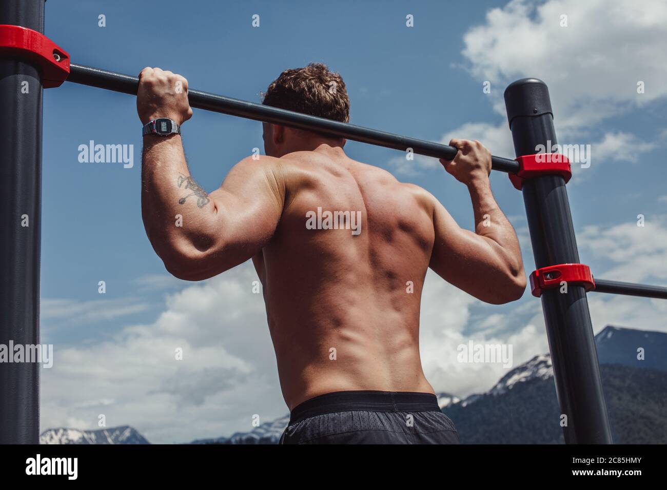 Portrait of a motivated shirtless sportsman doing pull-ups exercise on ...