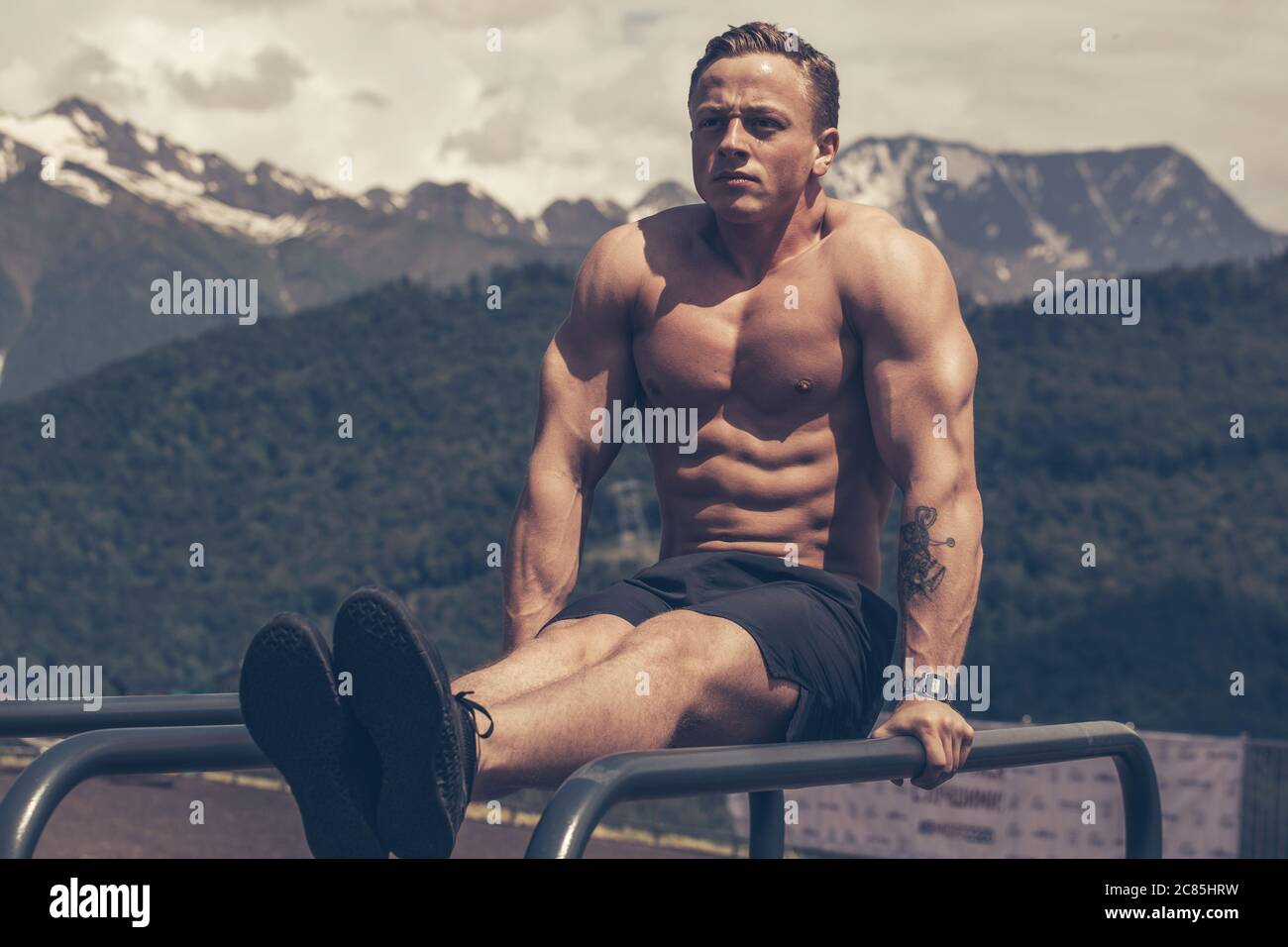 Portrait of blonde bodybuilder doing triceps dips on parallel bars at ...