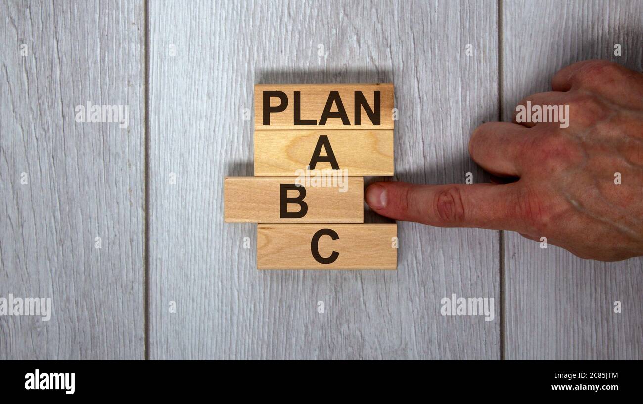 Wooden blocks form the words 'plan, a, b, c,' on woden table. Male hand ...