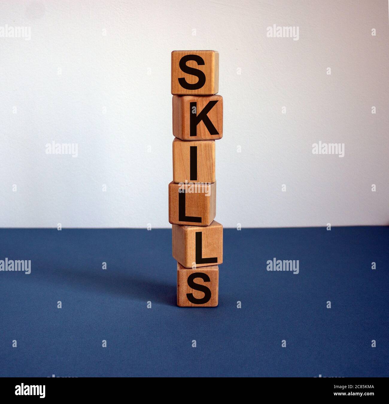 Wooden cubes with word 'skills' on blue table. Beautiful white ...