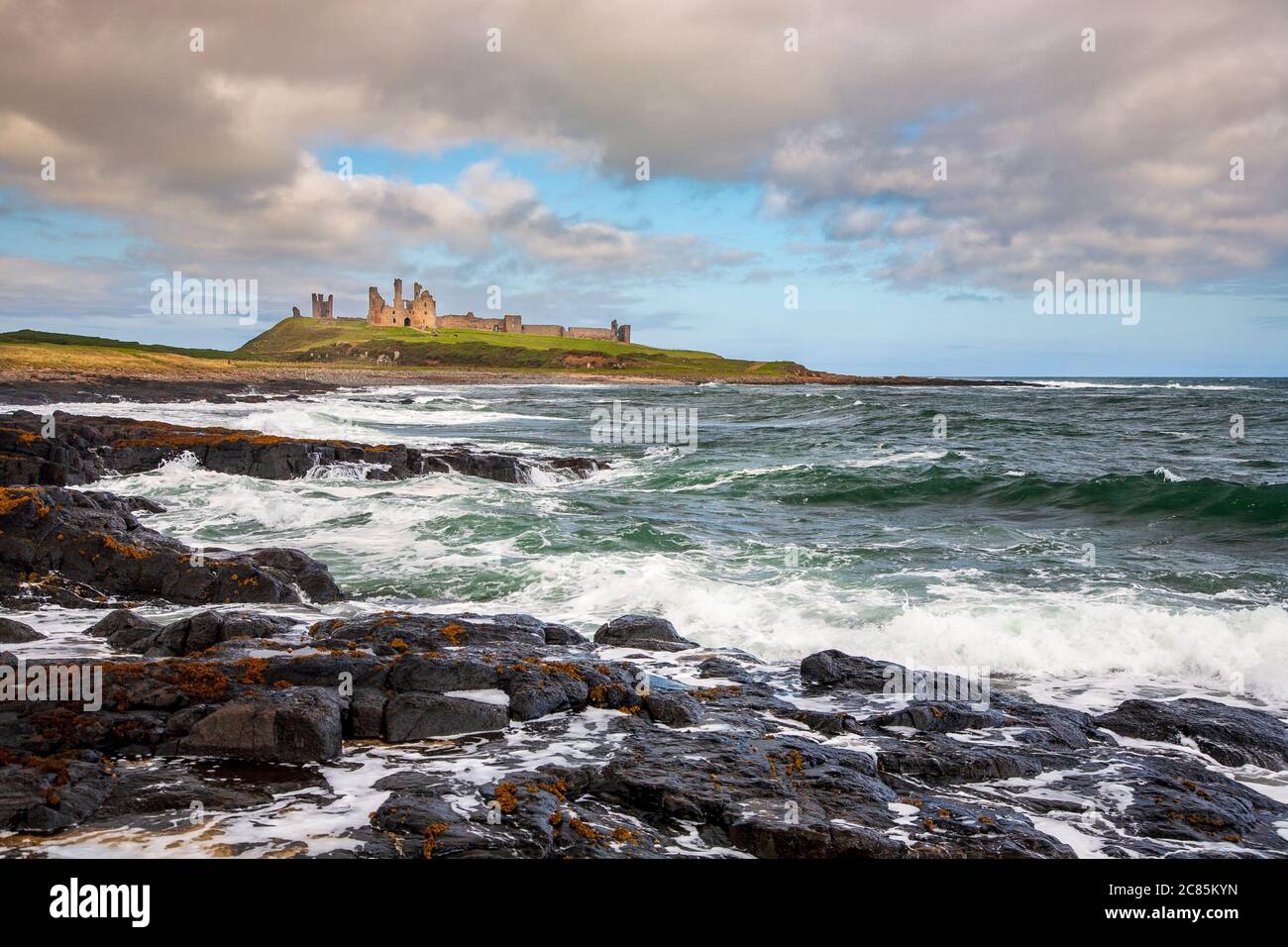 Waves breaking on the black Igneous rocks at Dunstanburgh Castle ...