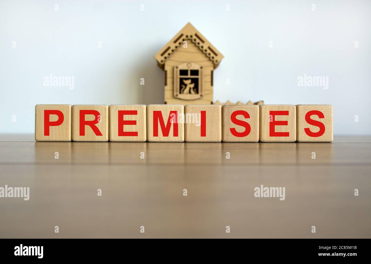 Wooden cubes form the word 'premises' near miniature house. Wooden ...