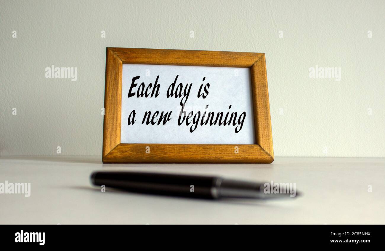 Wooden picture frame with inscription 'each day is a new beginning' on ...
