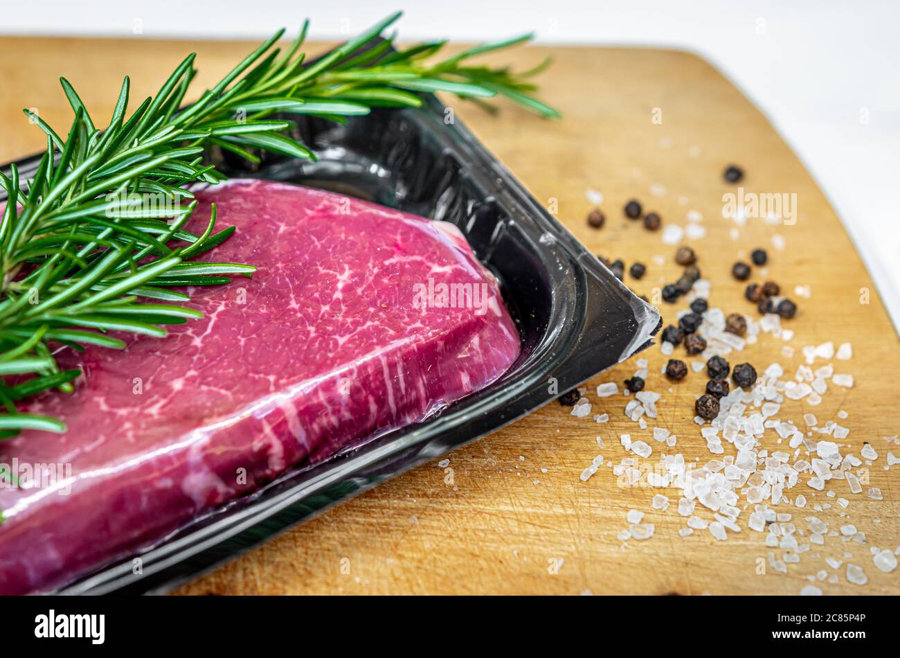 Beef steak in vacuum skin packaging and spices on wooden chopping board ...