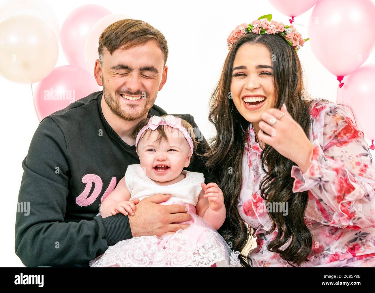 Horizontal lifestyle portrait of a young family on their daughter's ...