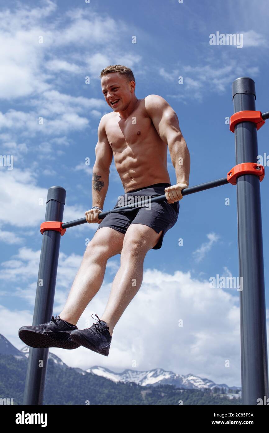 Portrait of a motivated shirtless sportsman doing pull-ups exercise on ...