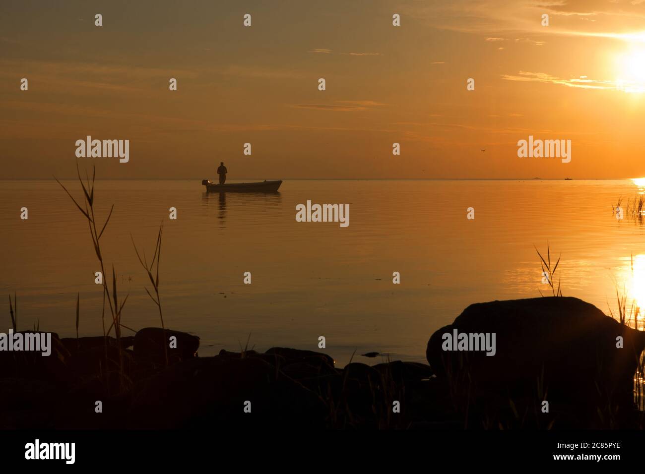 fisherman at the boat on golden sunset sea. beautiful and romantic ...