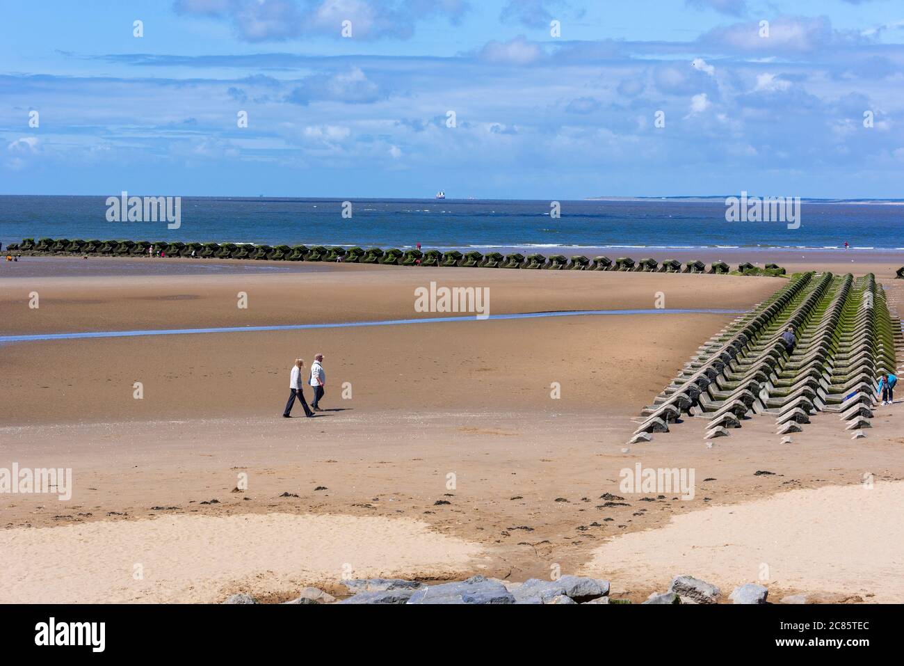 People strolling on New Brighton beach on the Wirral in the sunshine ...