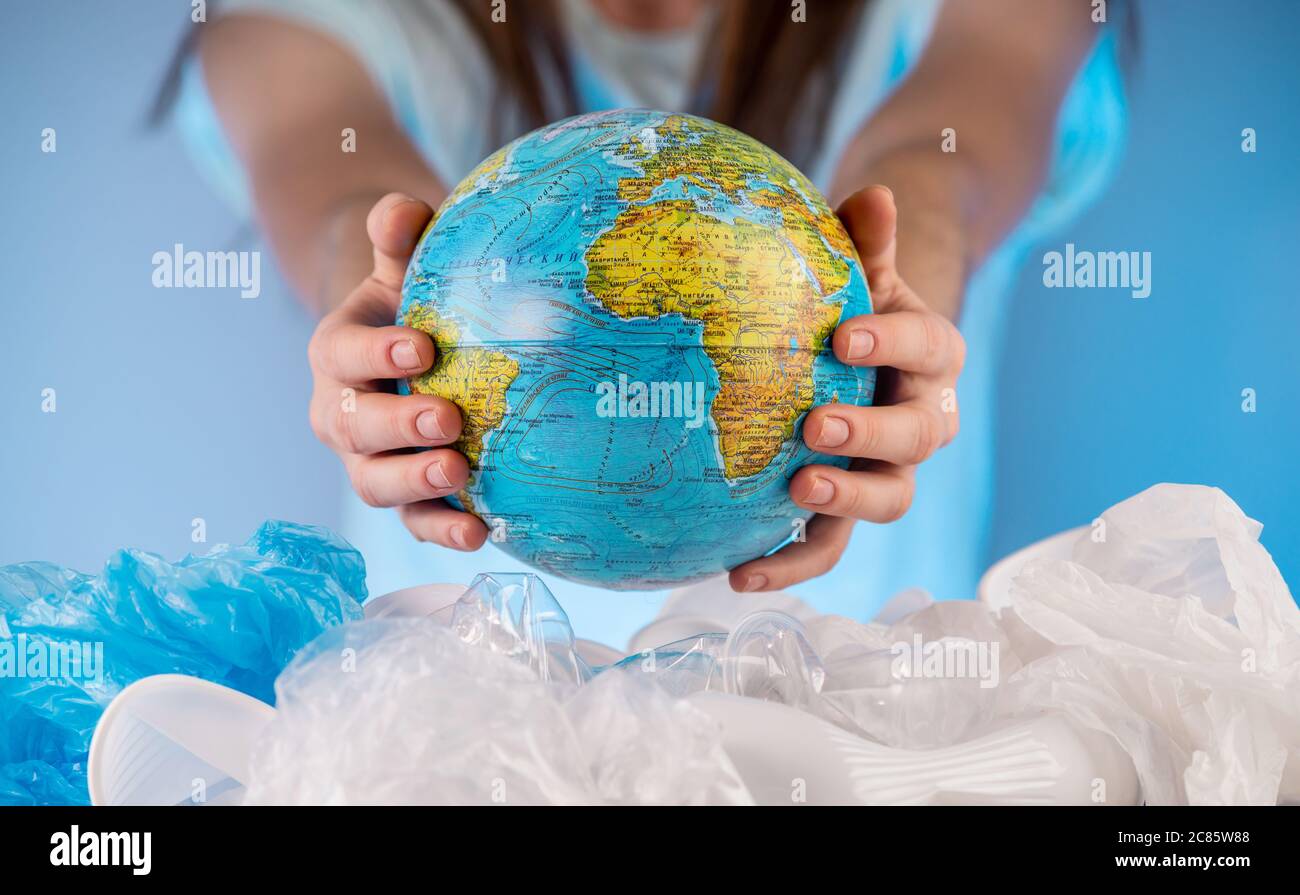 A woman is pulling out an Earth in form globe of a pile of plastic ...
