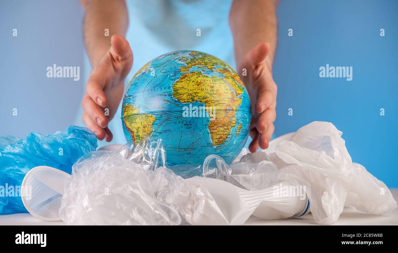 A woman is pulling out an Earth in form globe of a pile of plastic ...