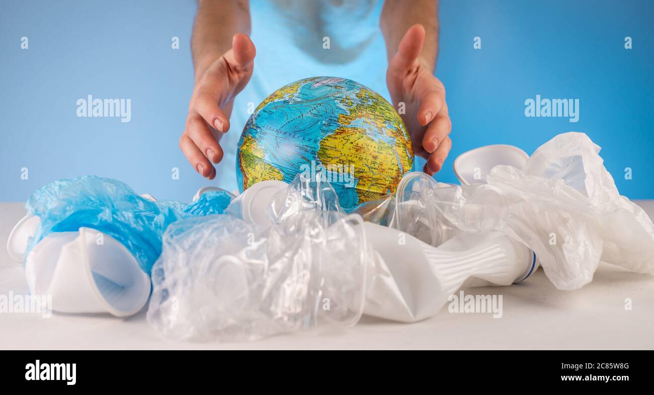 A woman is pulling out an Earth in form globe of a pile of plastic ...