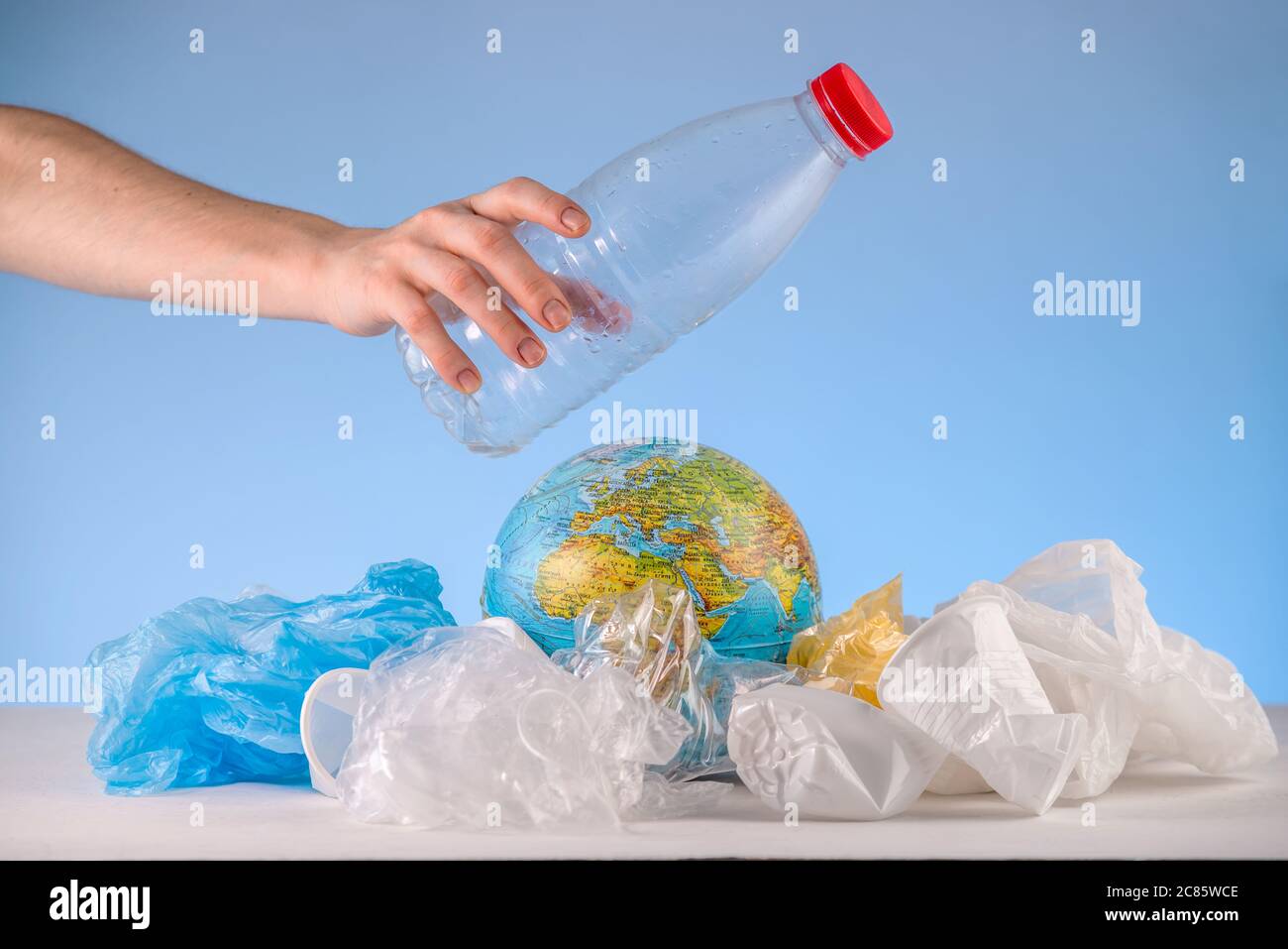 The hand is throwing the plastic on the Earth in the form of a globe ...