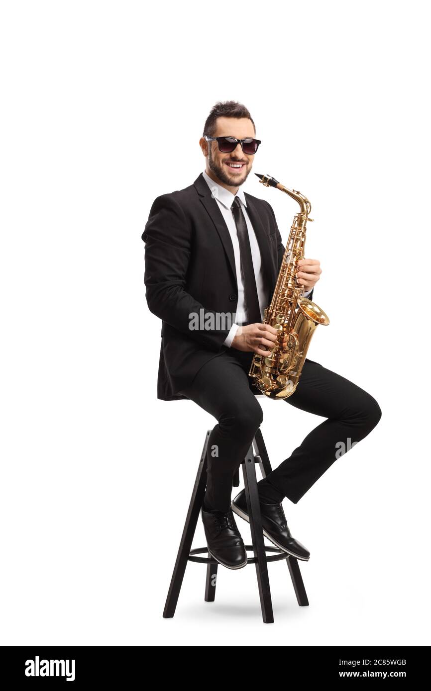 Full length portrait of a man sitting on a chair with a saxophone and ...