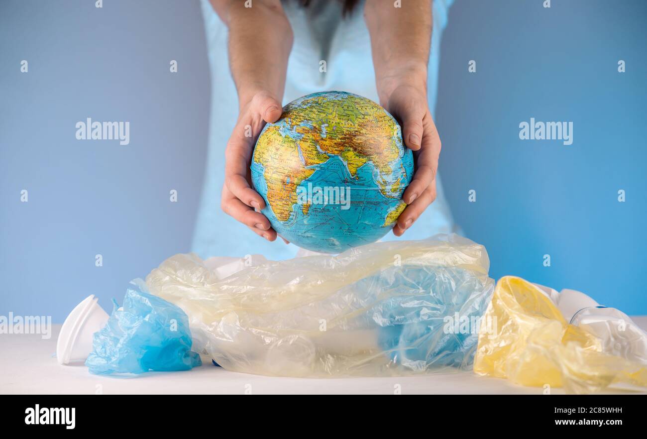 A woman is pulling out an Earth in form globe of a pile of plastic ...
