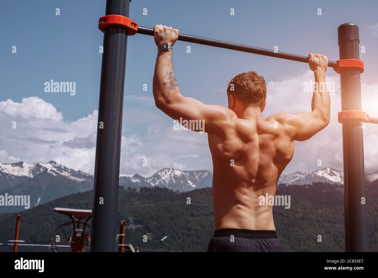 Portrait of a motivated shirtless sportsman doing pull-ups exercise on ...