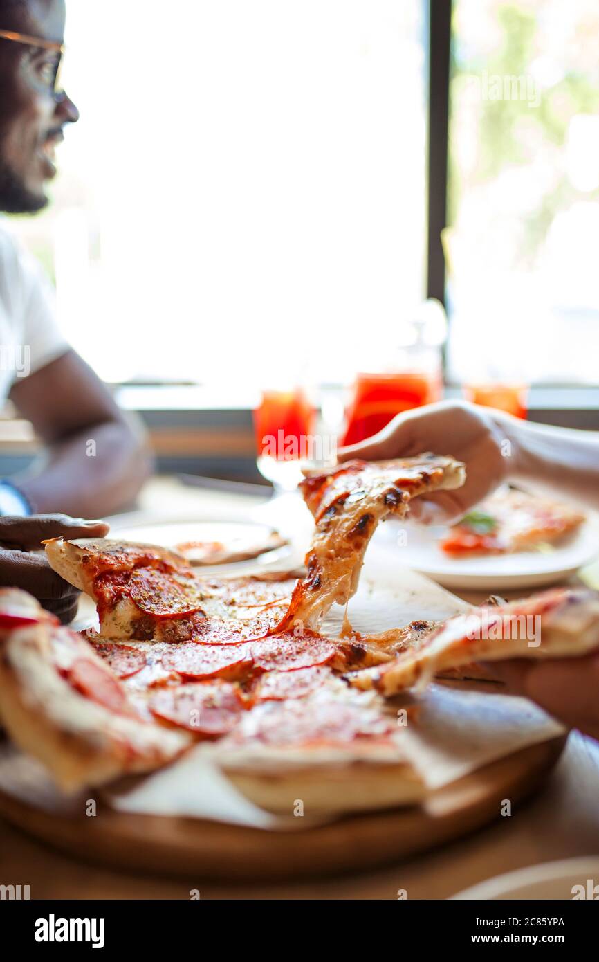 Lunch time at pizzeria, multiracial people grabbing slices of delicious ...