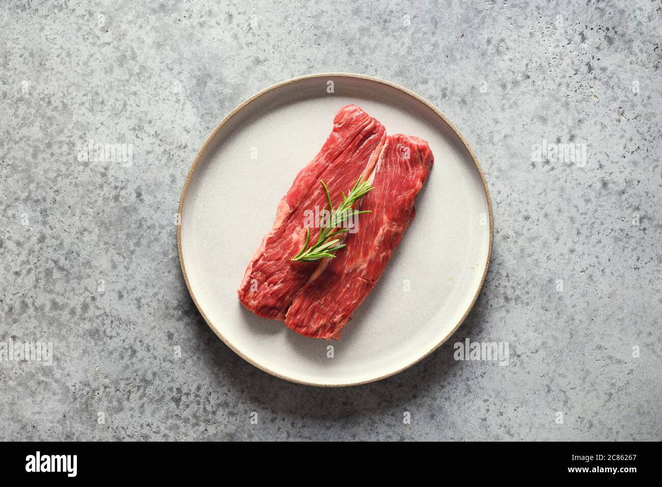 Raw ribeye steak with rosemary on grey Stock Photo - Alamy