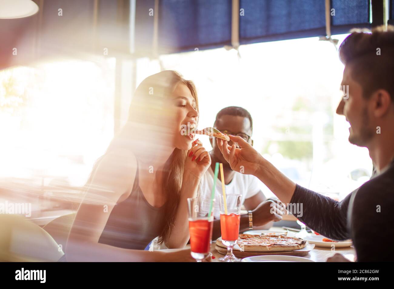 Two Young Couples Having Fun Feeding Each Other With Slice Of Pizza