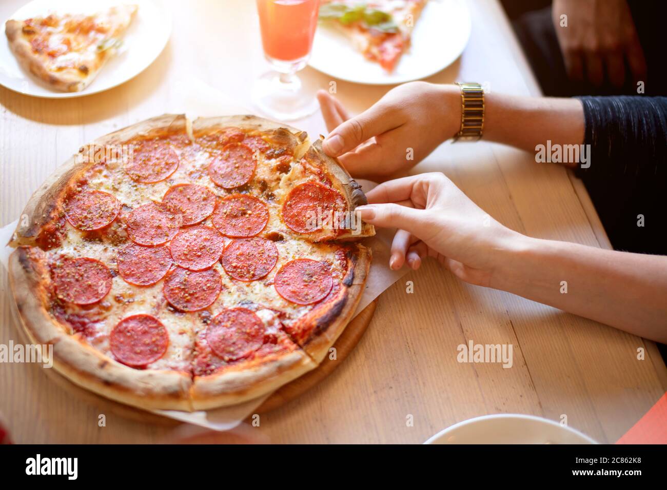 Human hands close up grabbing pizza slices from wooden background Stock ...