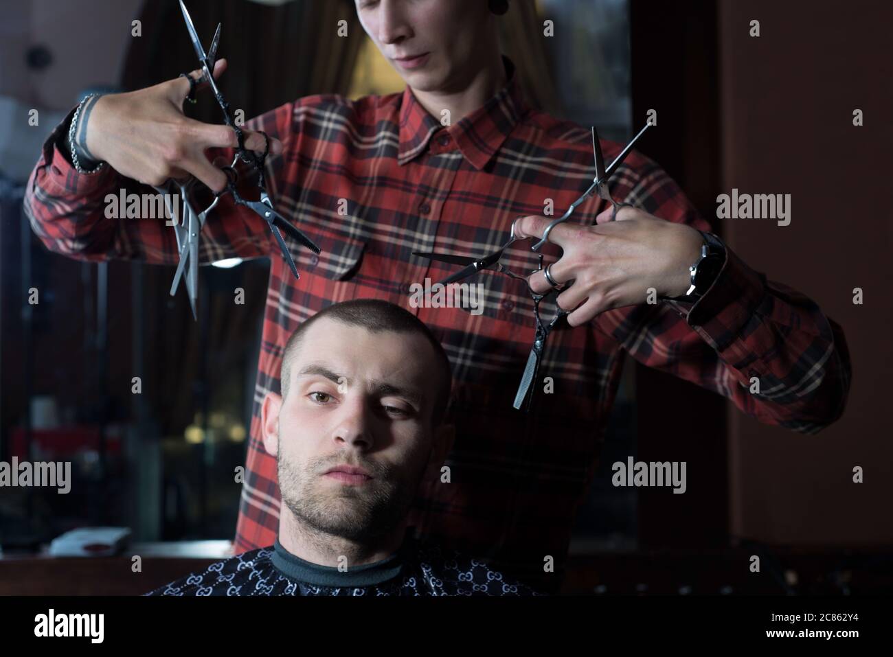 hairdresser a young guy with many scissors in his hand, cuts with a ...