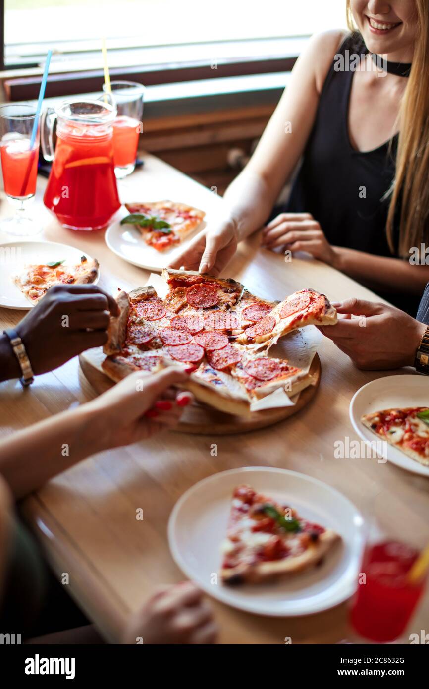 Lunch time at pizzeria, multiracial people grabbing slices of delicious ...