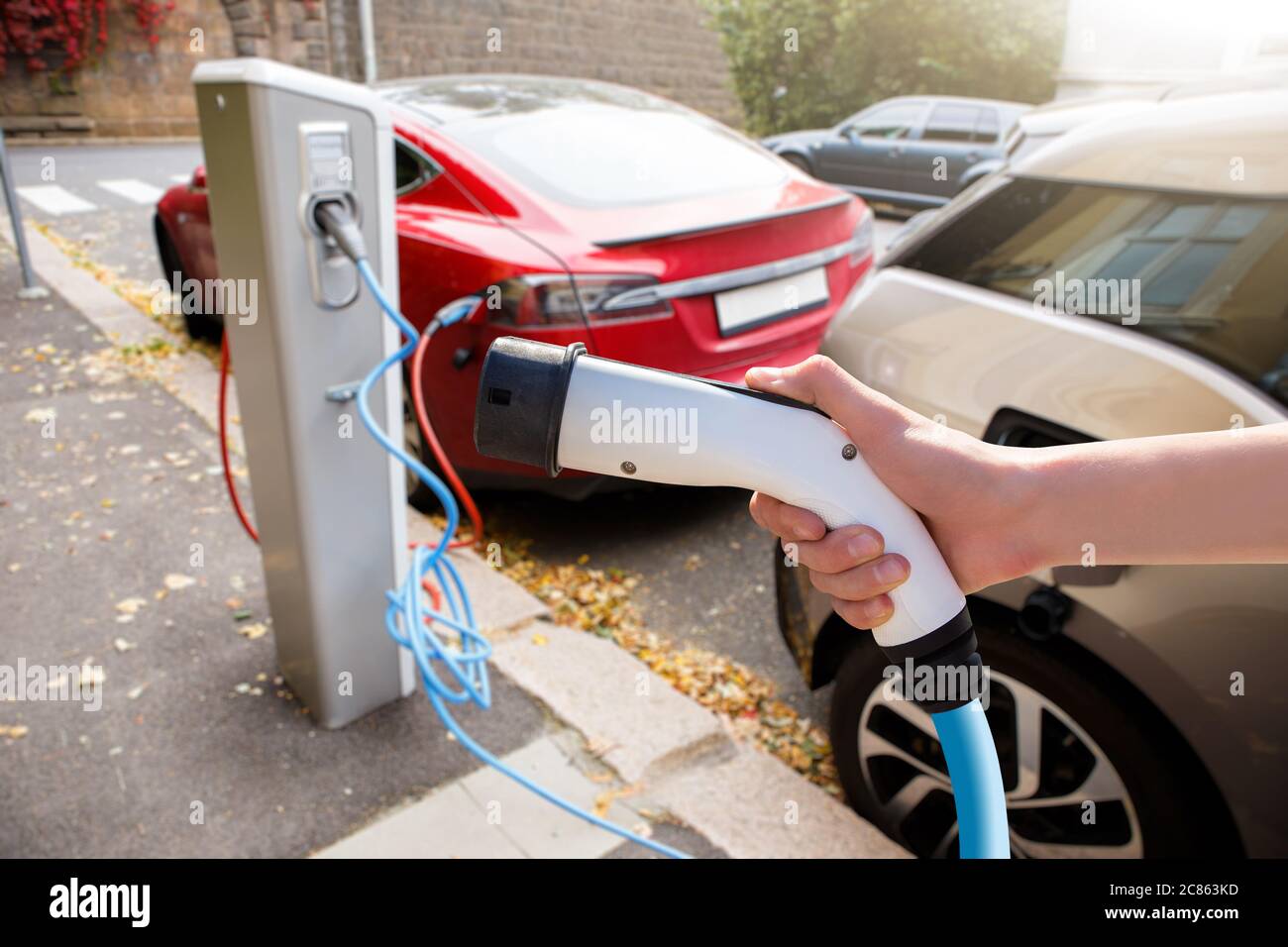 Hand with charger on a background of electric car Stock Photo - Alamy